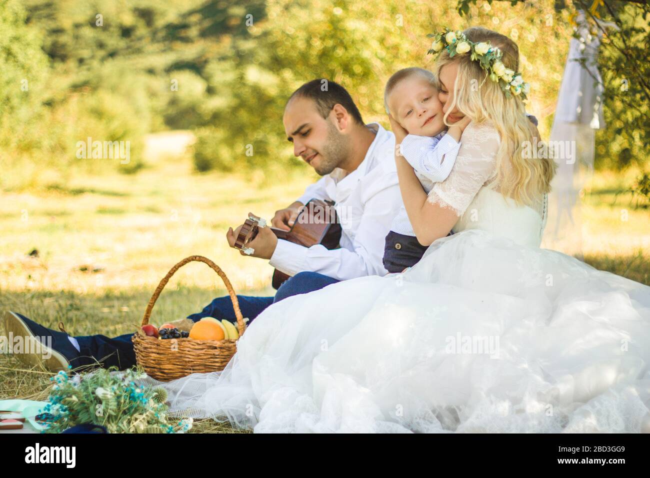 Picnic style outdoor wedding. Groom playing on guitar, young attractive ...