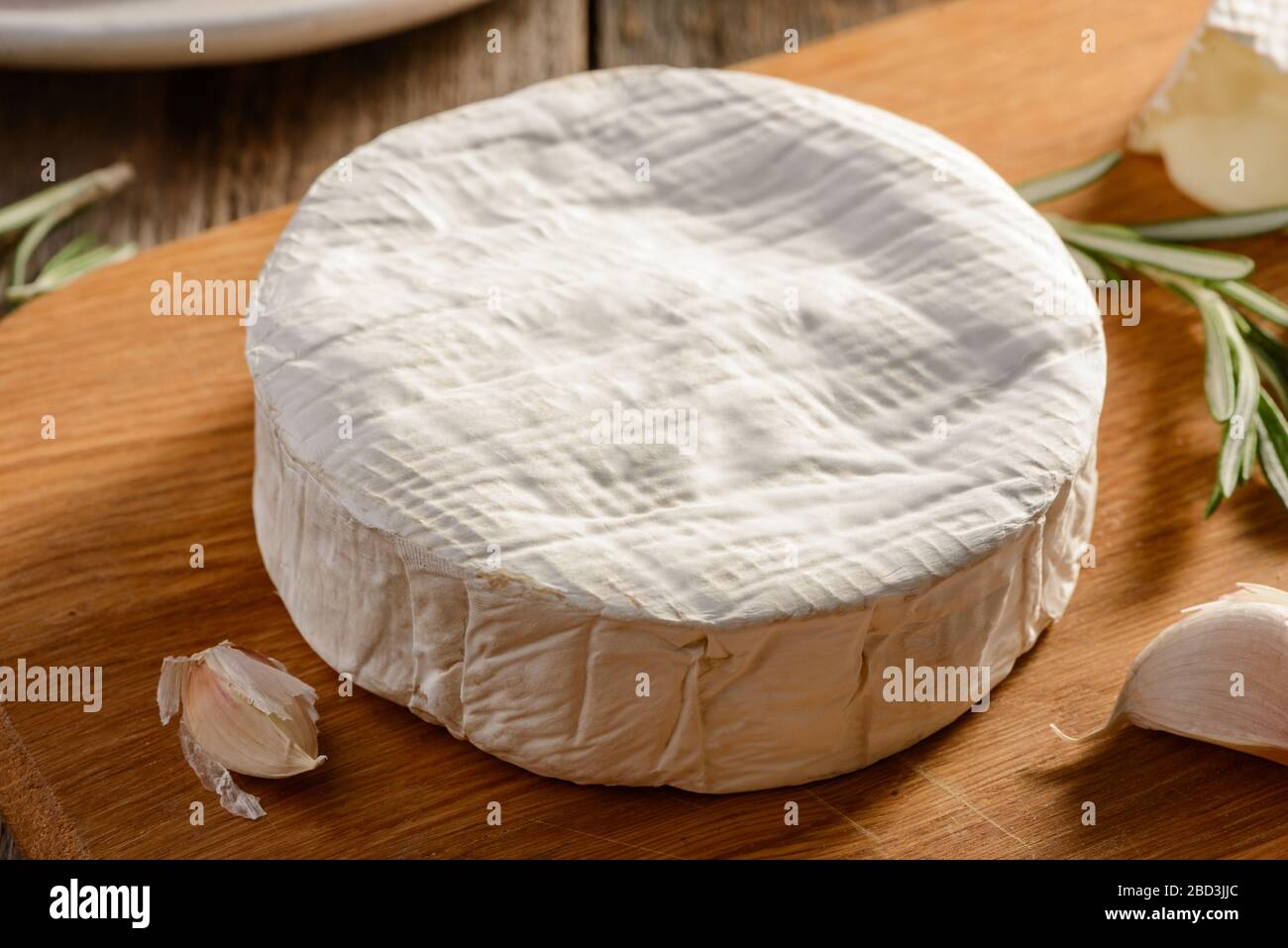 Closeup on a Brie cheese wheel, garlic and rosemary Stock Photo - Alamy
