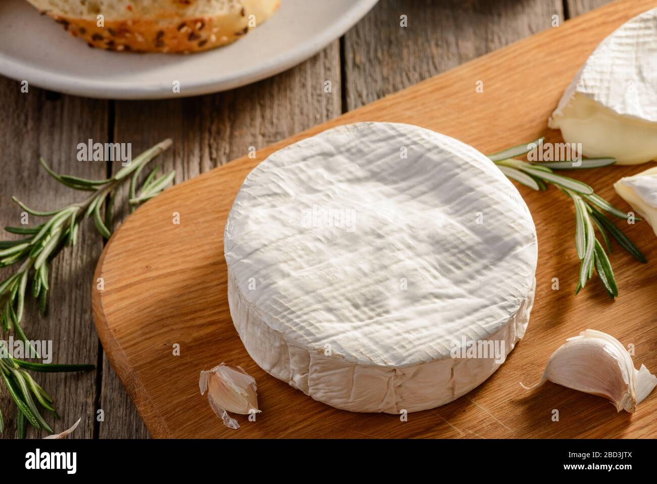 Closeup on a whole wheel of Brie cheese, garlic and rosemary Stock ...