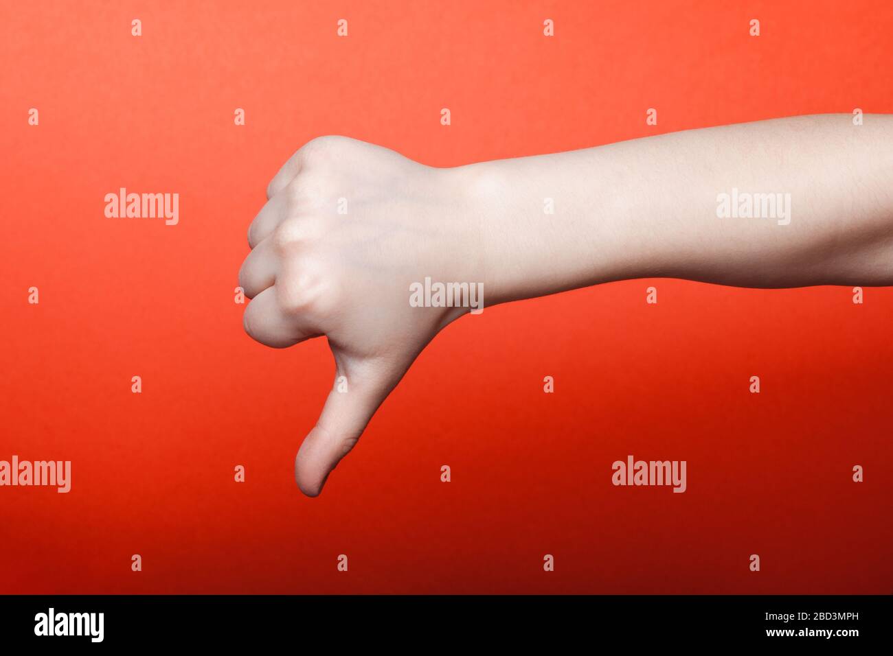 Child hand shows thumb down on red background Stock Photo - Alamy