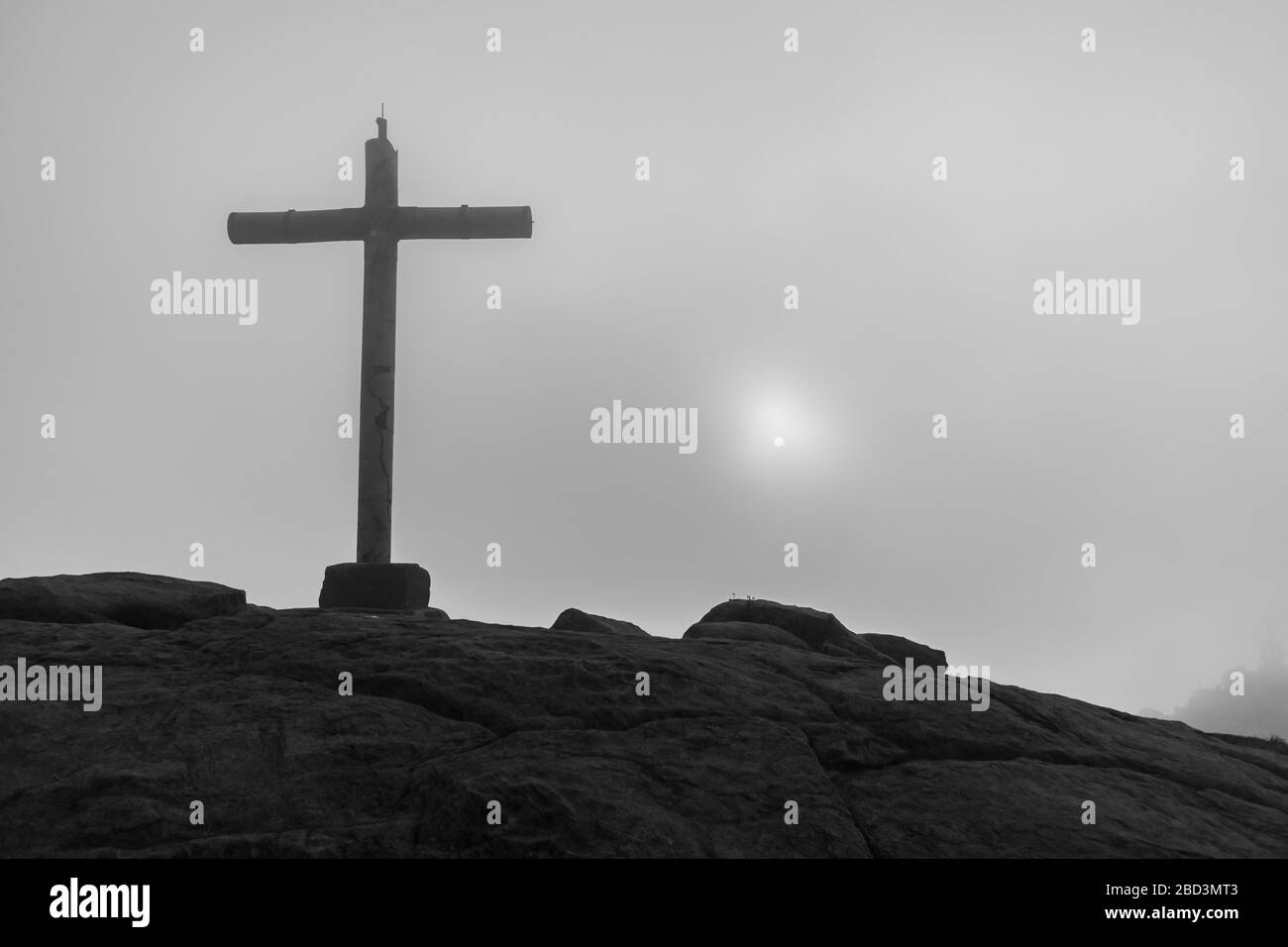 Large concrete cross on top of the peak of Bandeira, with sun between ...