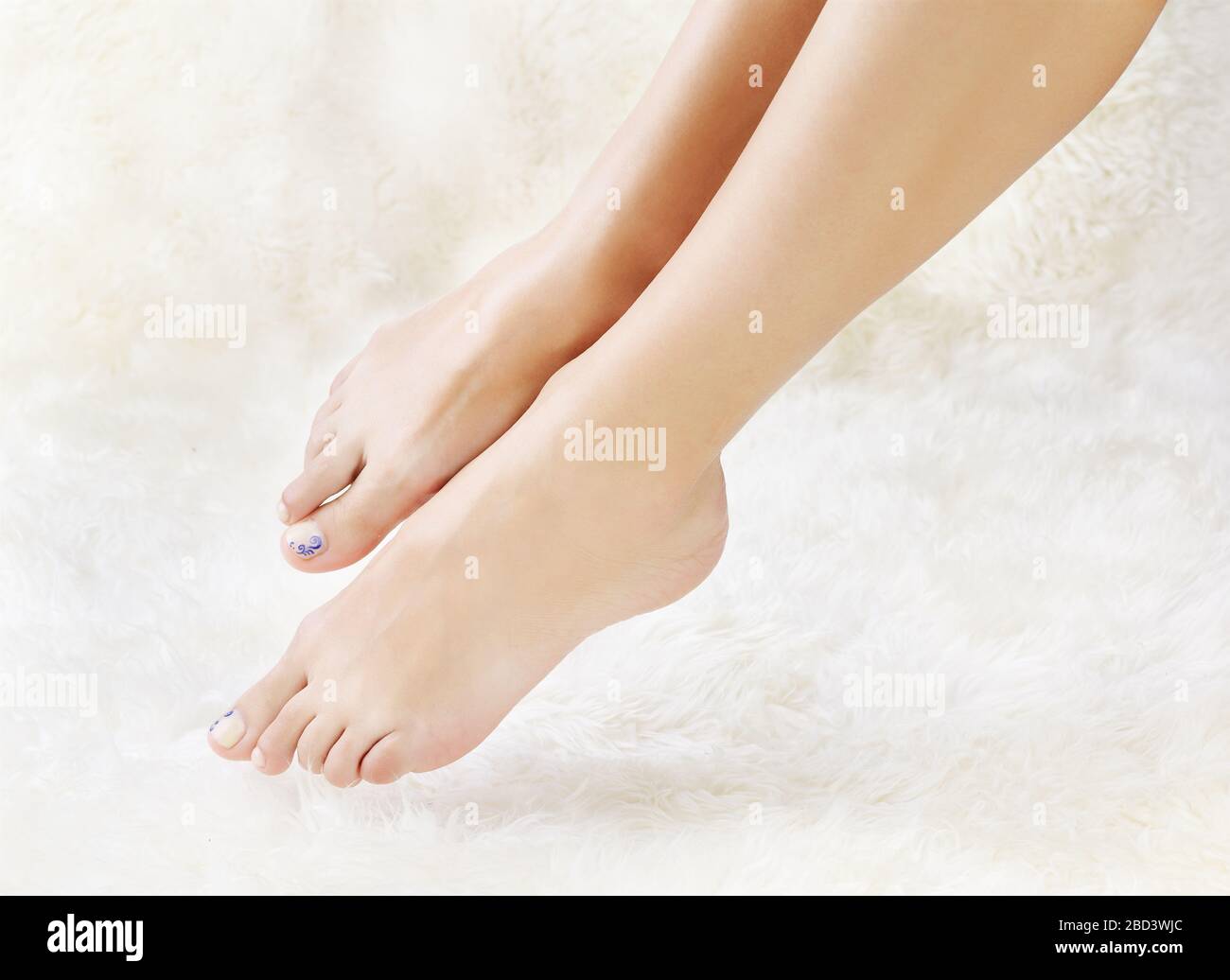 body part shot of beautiful healthy young woman's legs on white fur ...