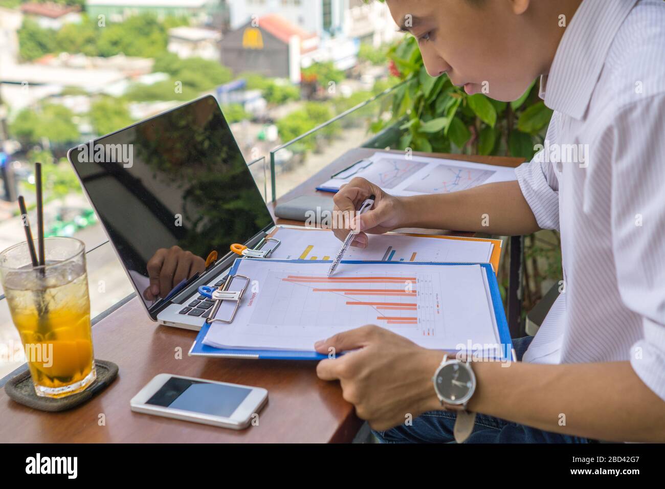 Side view of Asian businessman checking financial number on document ...