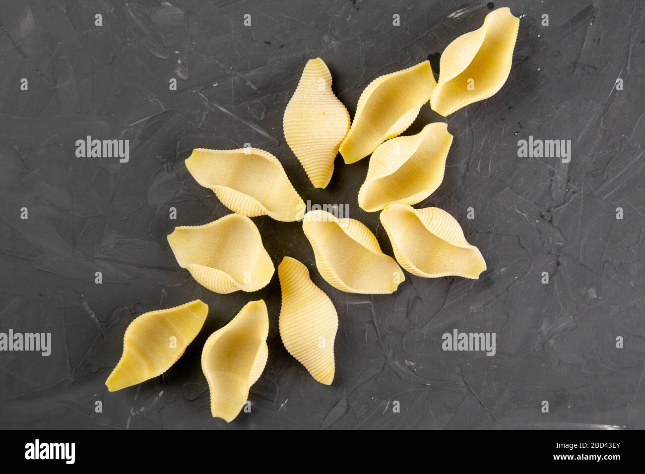 Raw conchiglie or seashell shaped pasta isolated on black background ...