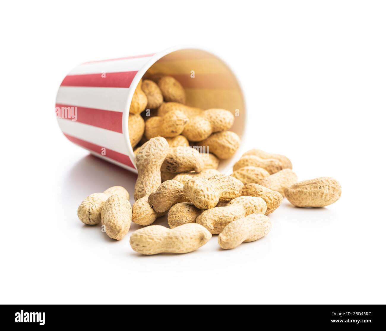 Tasty unpeeled peanuts in striped paper cup isolated on white ...