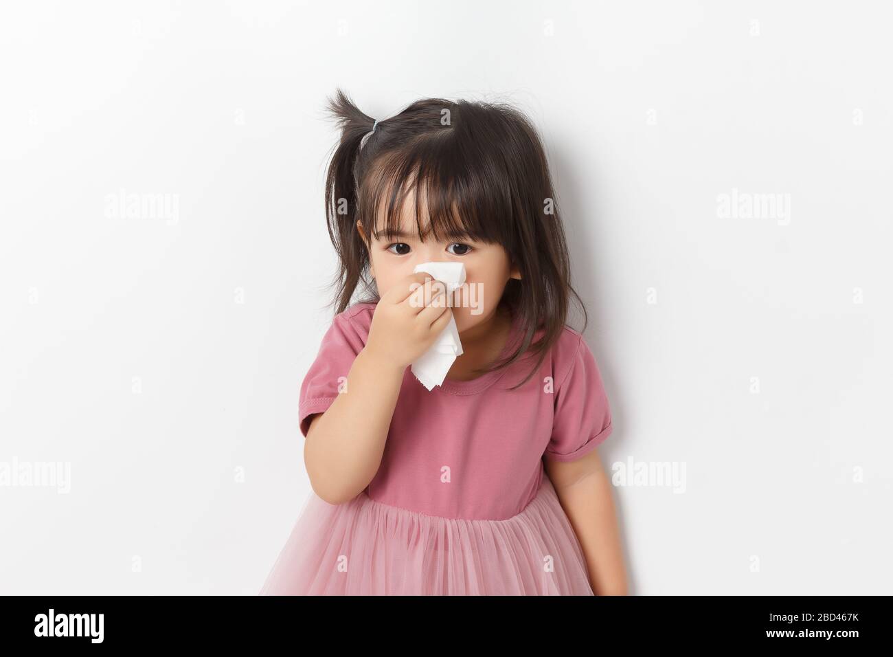 Little asian girl holding a tissue and blow her nose. Kid with cold ...