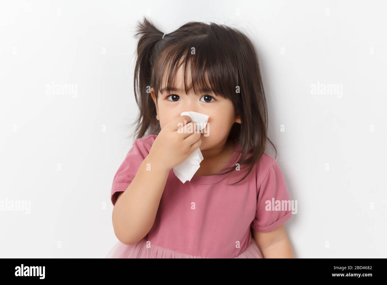 Little asian girl holding a tissue and blow her nose. Kid with cold ...