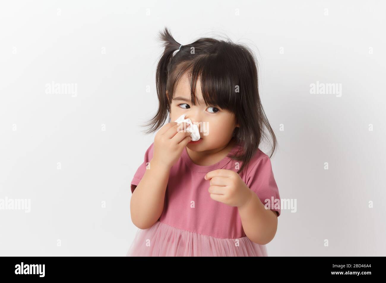 Little asian girl holding a tissue and blow her nose. Kid with cold ...