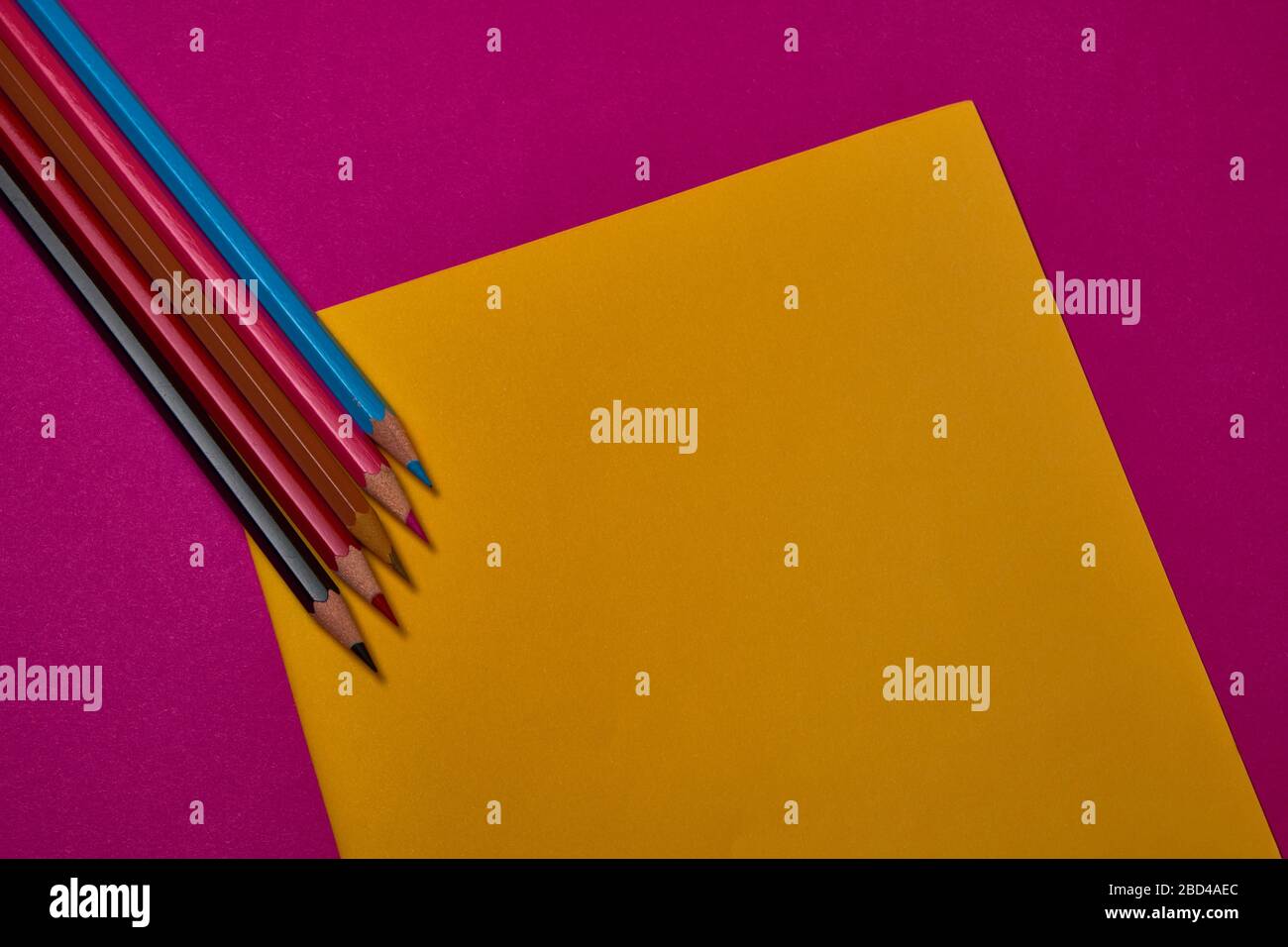 Multi colored crayons at yellow and magenta background with copy space ...
