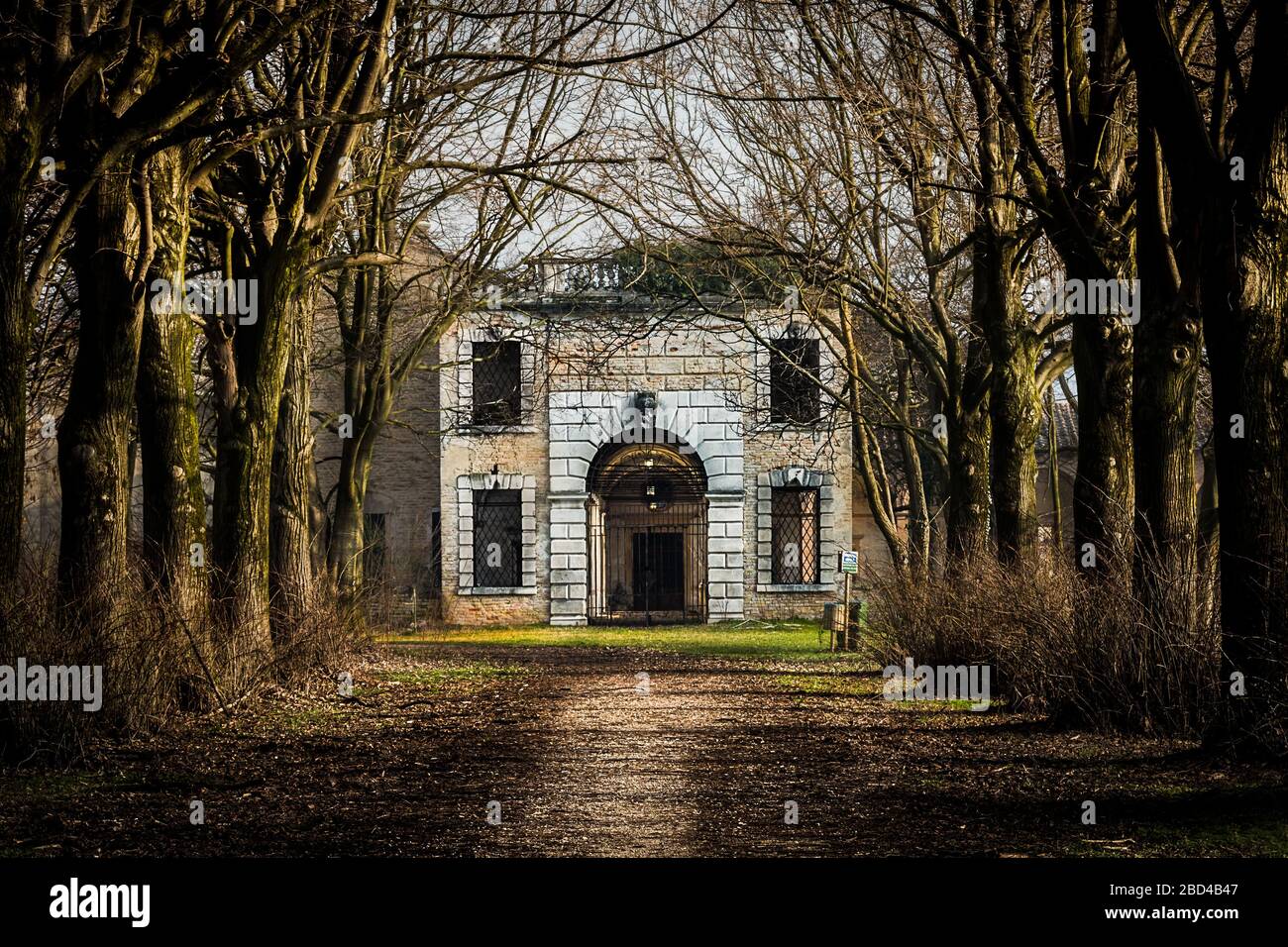Close up of a tree lined dirt road leading to the portal of an ancient ...