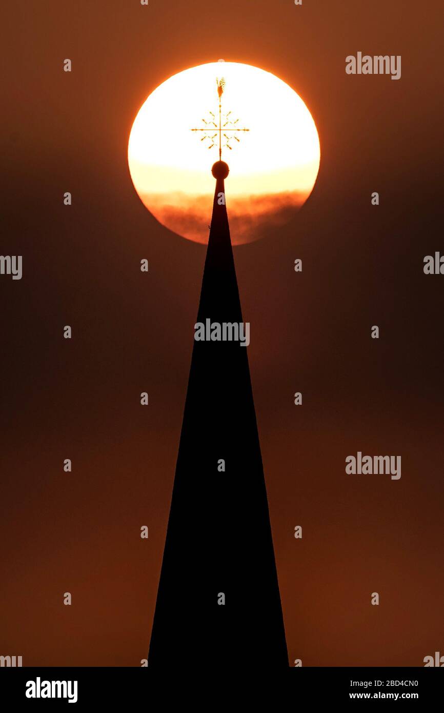 Cologne, Germany. 07th Apr, 2020. The sun rises behind the steeple of ...