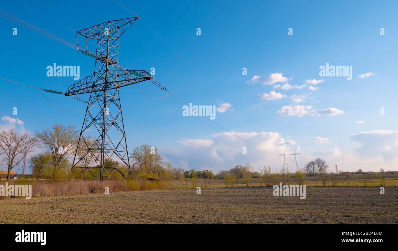 High voltage power line in a field with clouds in the background. High ...