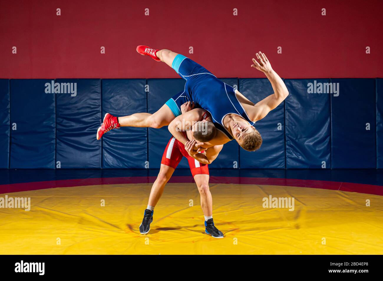 Two greco-roman wrestlers in red and blue uniform making a suplex ...
