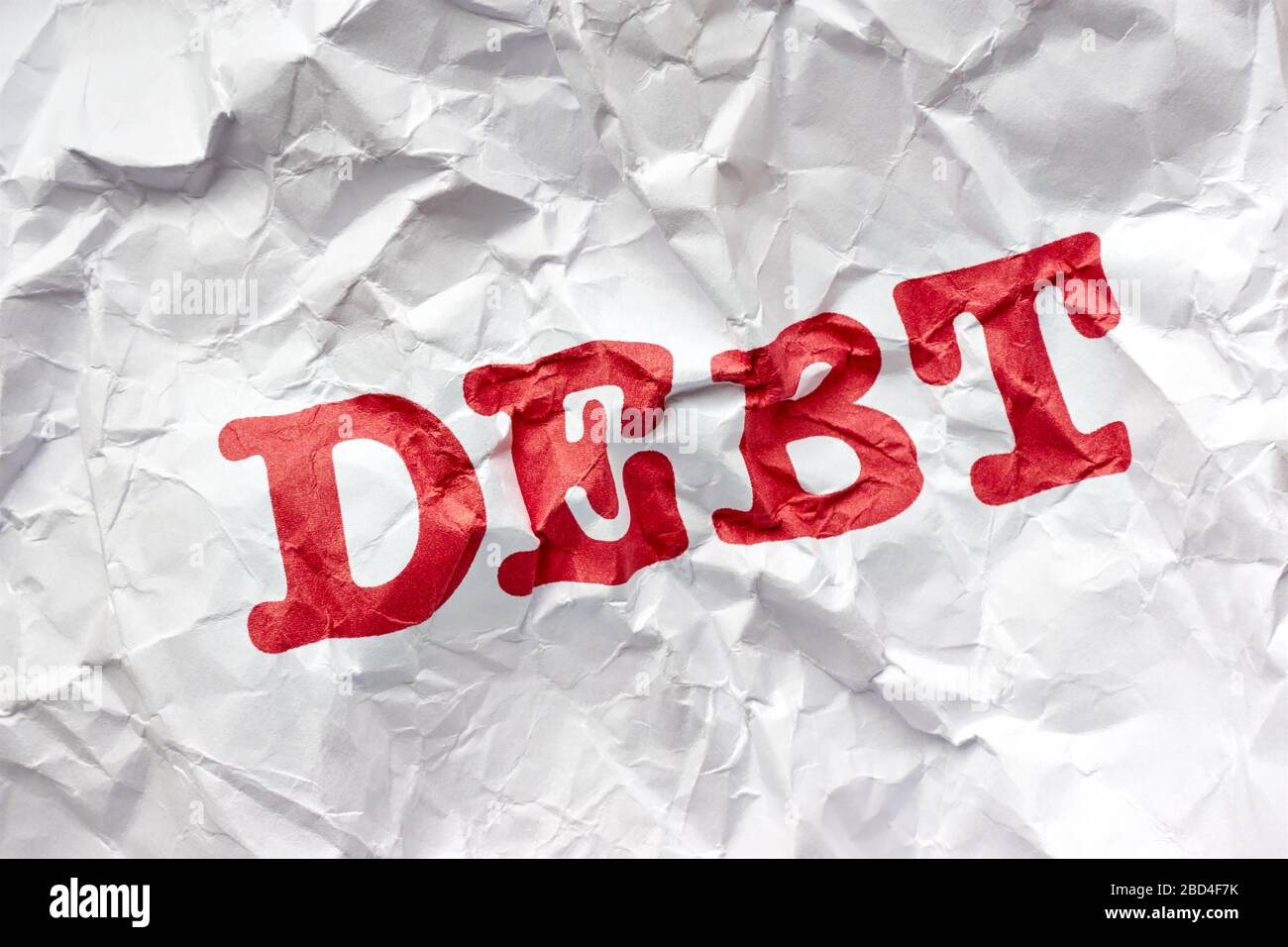 Wrinkled white paper with the word debt printed in red. Concept of debt ...