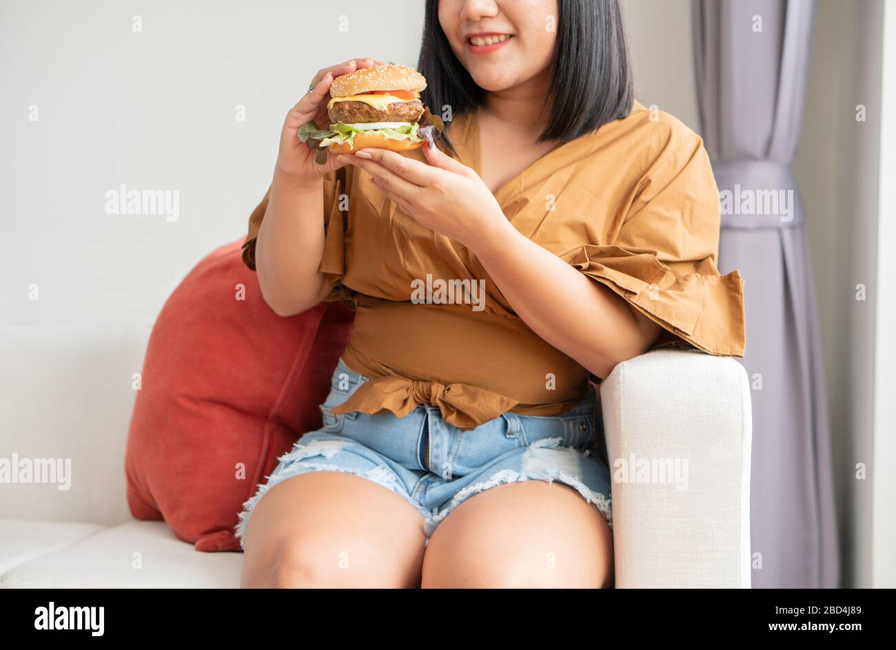 Hungry Overweight Woman Smiling And Holding Hamburger And Sitting In