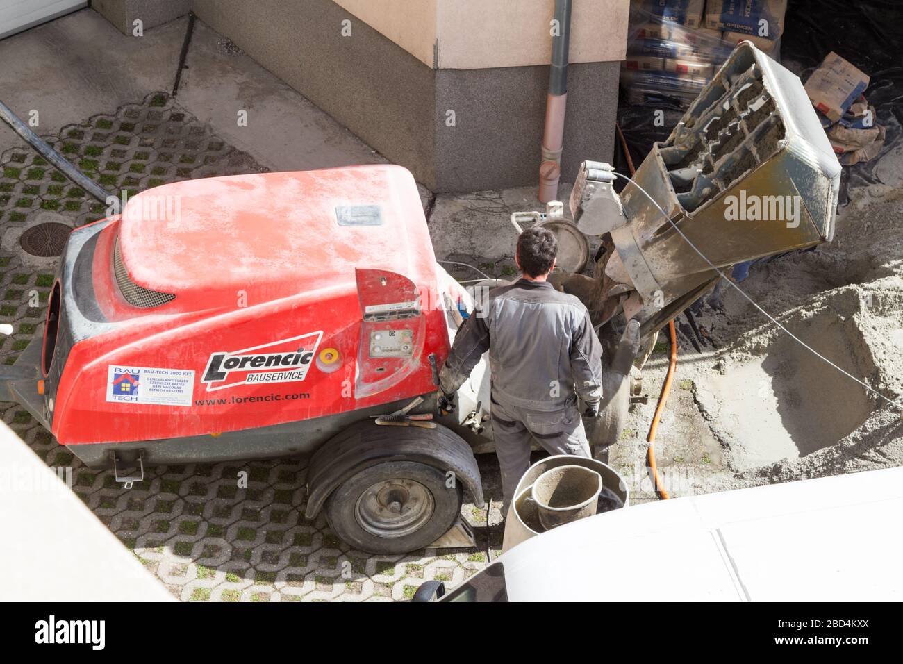 Worker using Lorencic screed conveyor, from window above, home flat ...