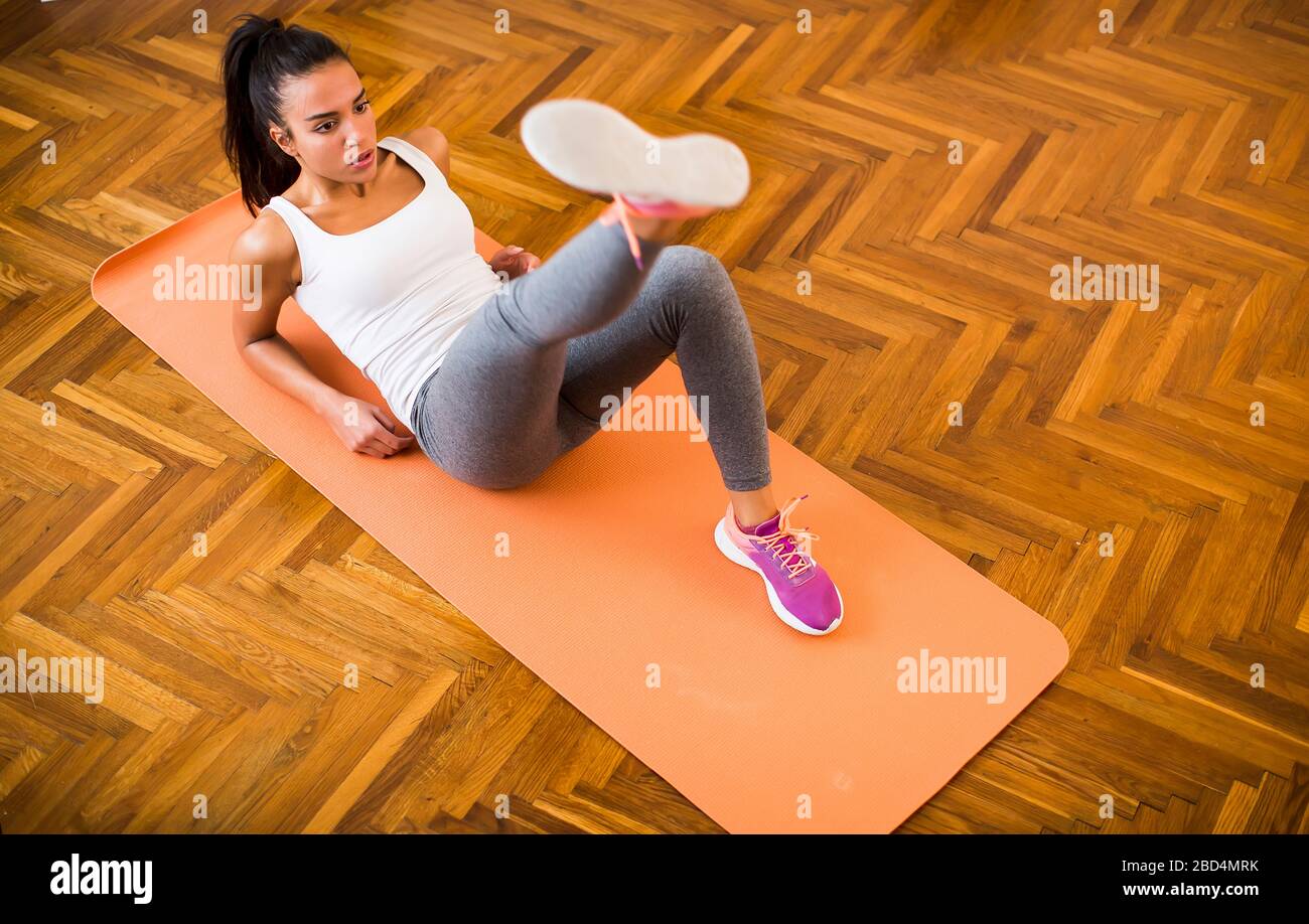 Cute young attractive woman practicing exercises on the floor at home ...
