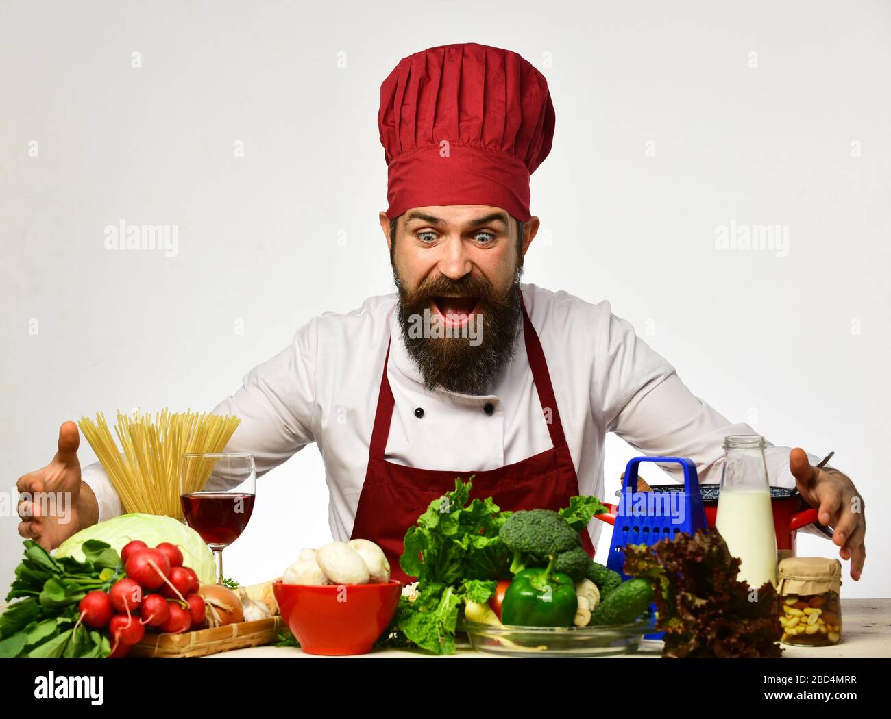 Chef prepares meal. Cook with excited face in burgundy uniform sits by ...