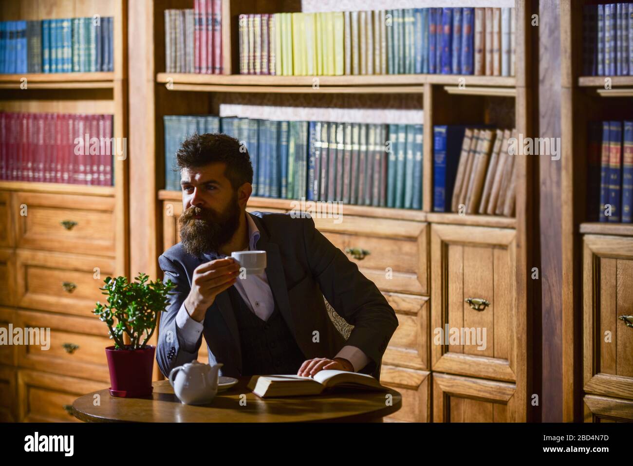 Oldfashioned man holds cup with tea. Man in classic suit sits in ...