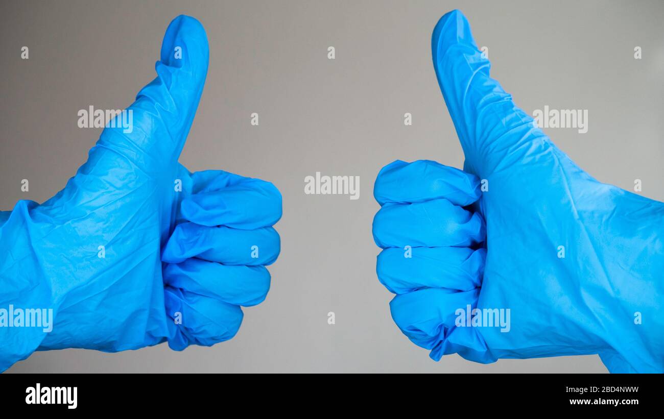 Two hands in blue gloves showing thumbs up - close up Stock Photo - Alamy
