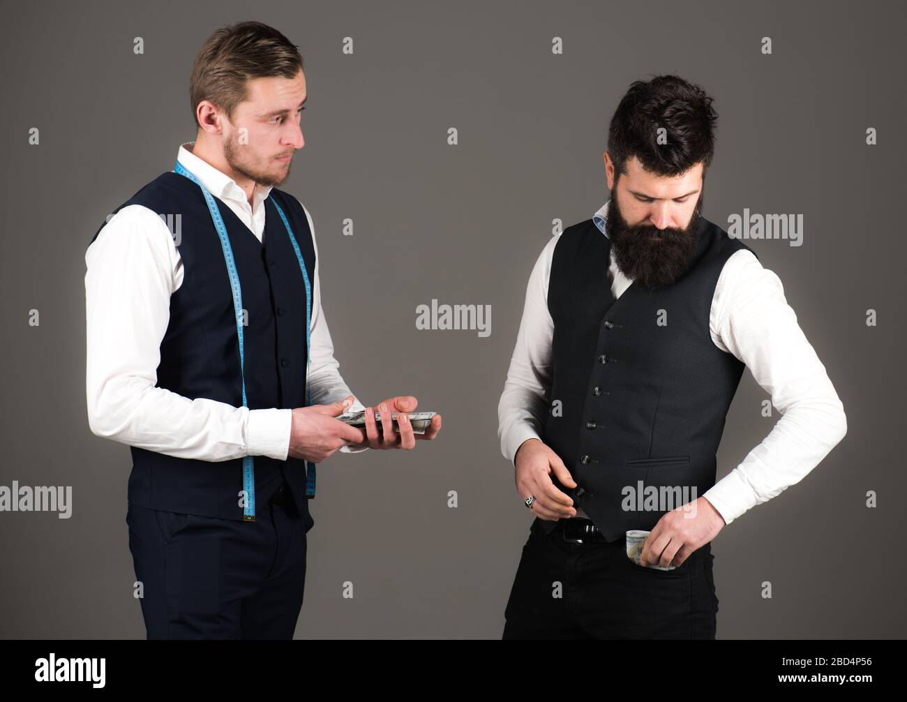 Overpayment concept. Man with beard pay to macho with measuring tape ...