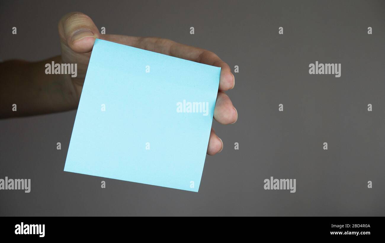 Hand holding a blank sticker. Square paper with space for text in the ...
