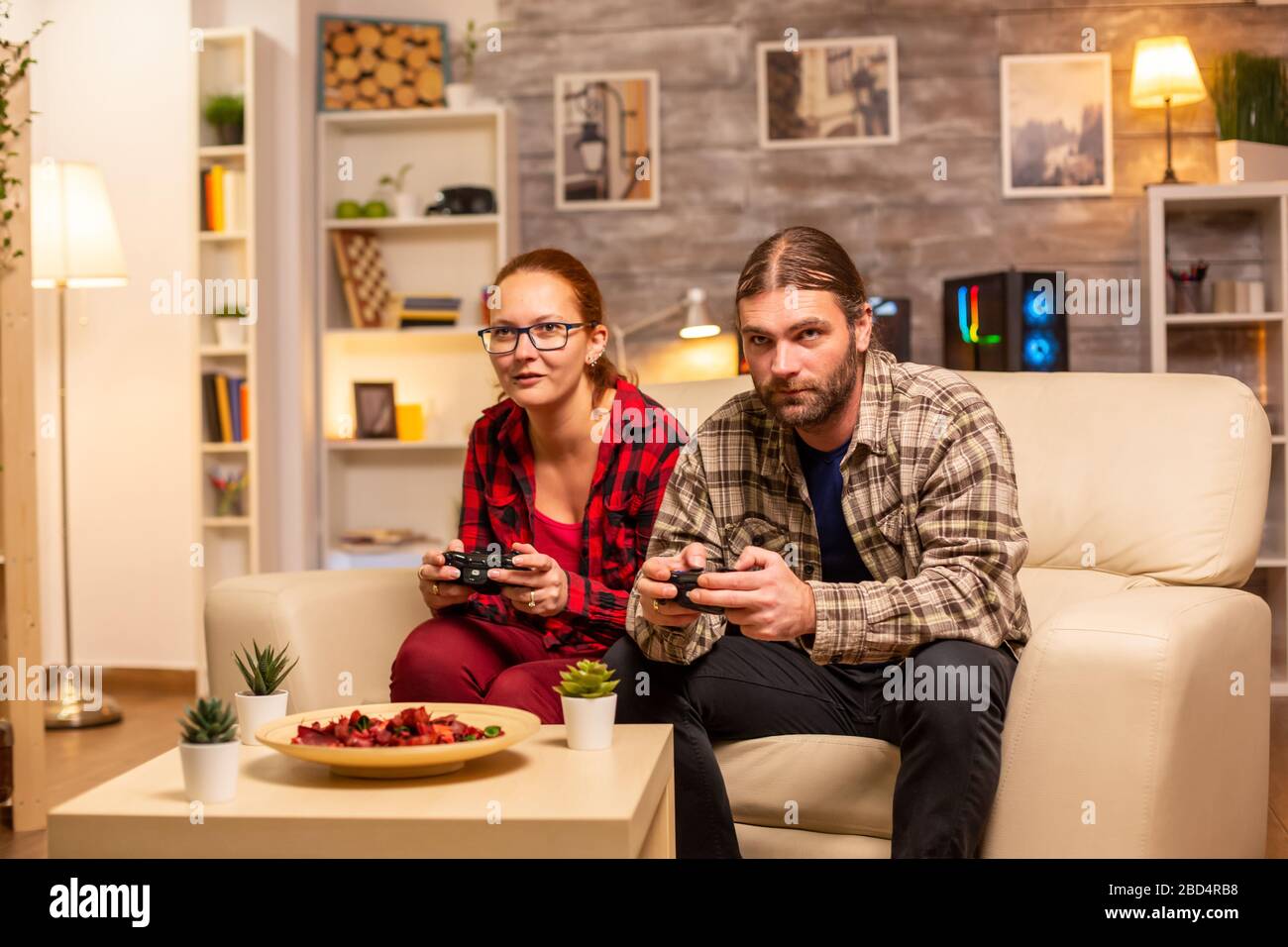 Gamers couple playing video games on the TV with wireless controllers ...