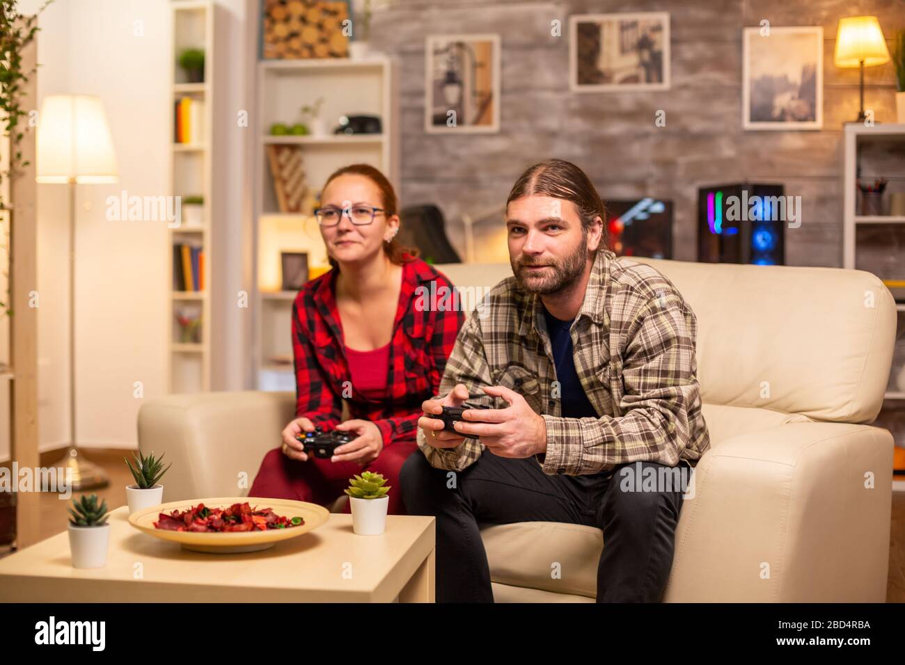 Gamers couple playing video games on the TV with wireless controllers ...