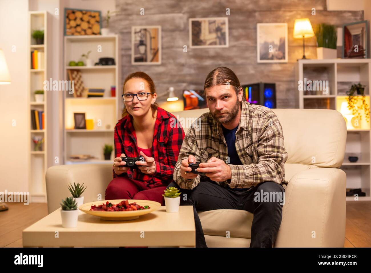 Gamers couple playing video games on the TV with wireless controllers ...