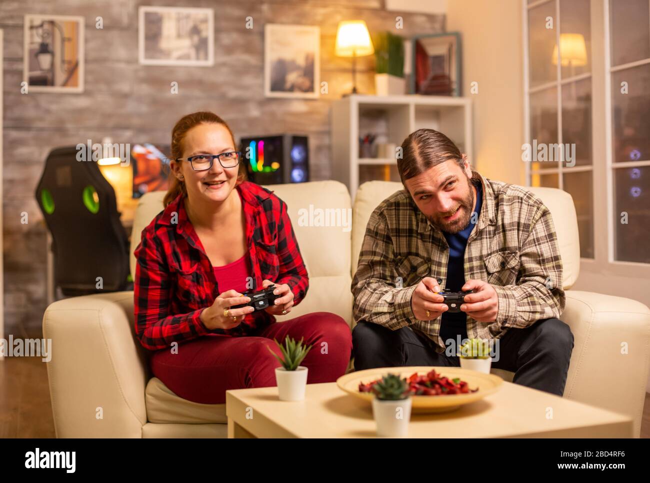 Gamers couple playing video games on the TV with wireless controllers ...