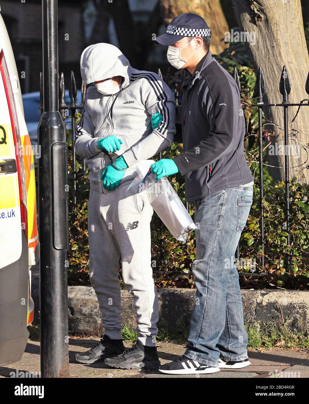 Police officers take a suspect away during a raid at an address in ...