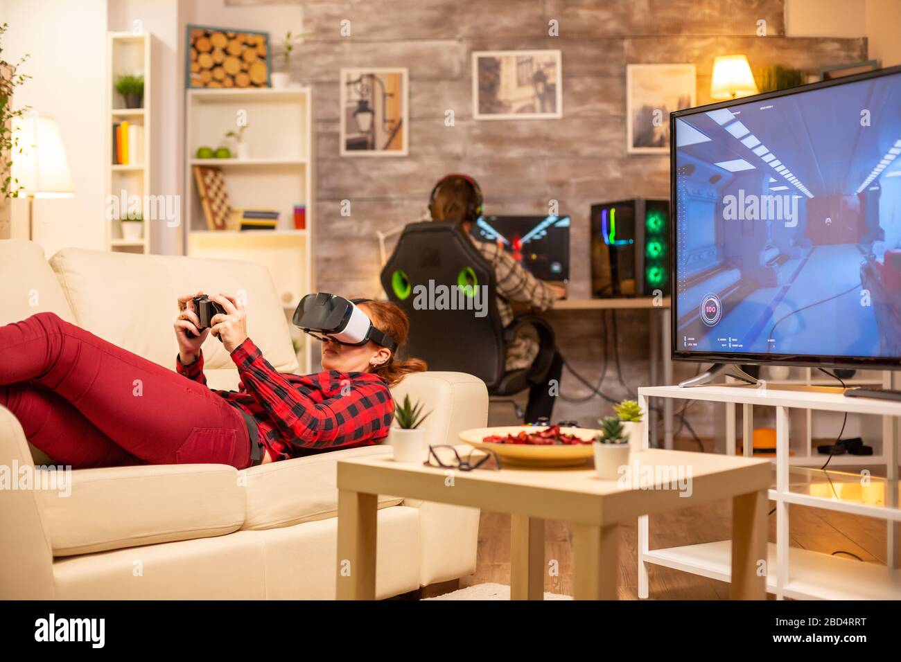 Woman lying on the sofa late at night in living room playing video ...