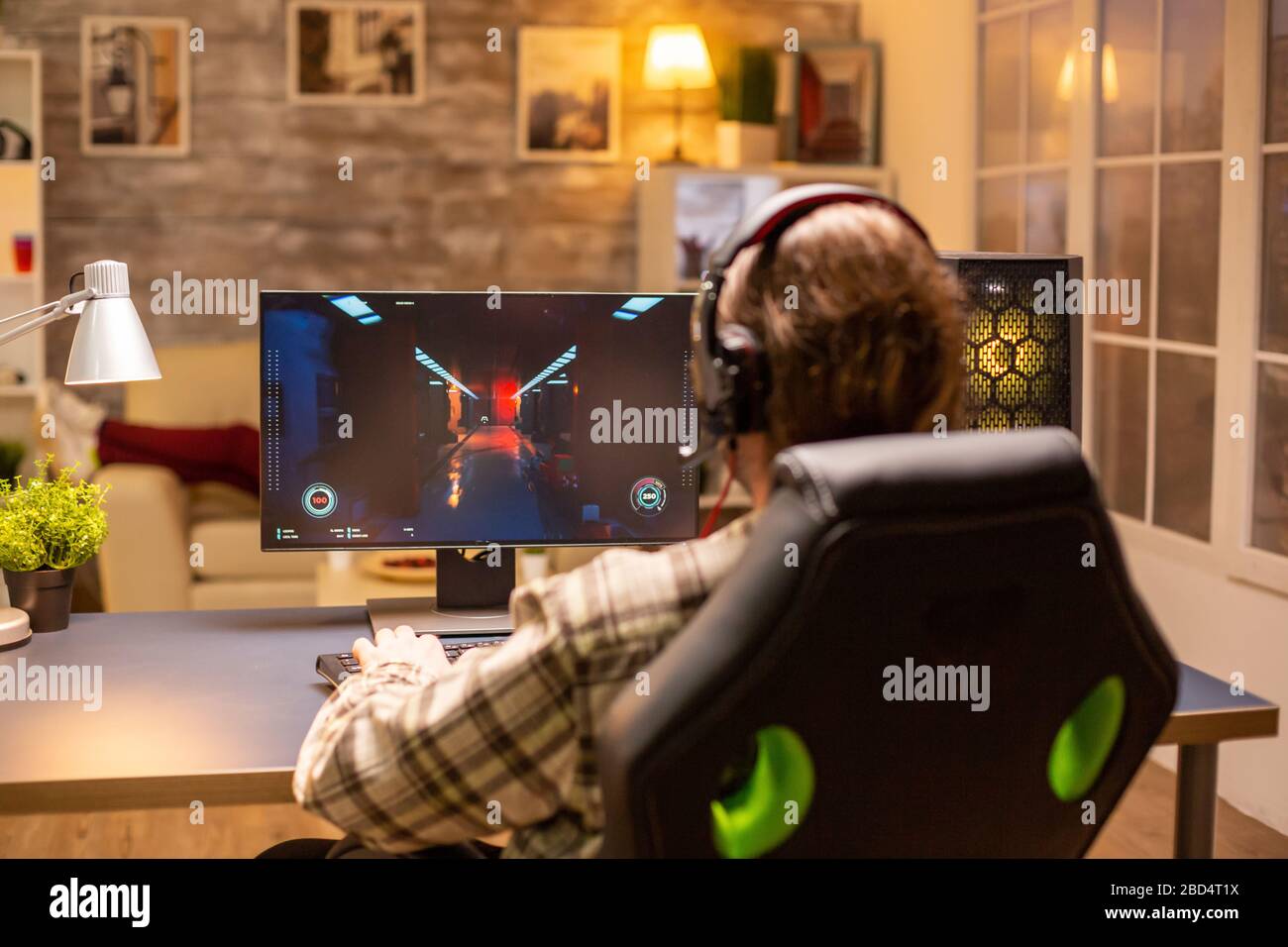 Back view of gamer male playing a shooter on his powerful PC computer ...