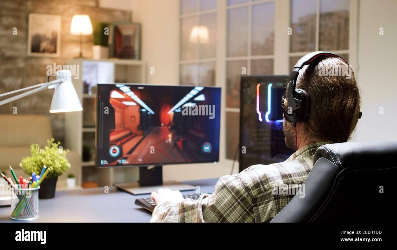 Professional gamer with long hair puts his headphones with a mic on and ...