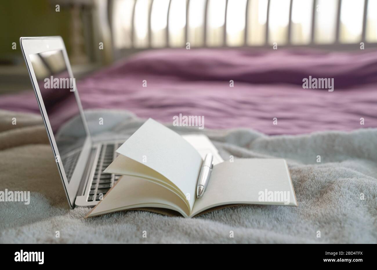 Computer laptop, and notepad on top of bed. Work at home concept Stock ...