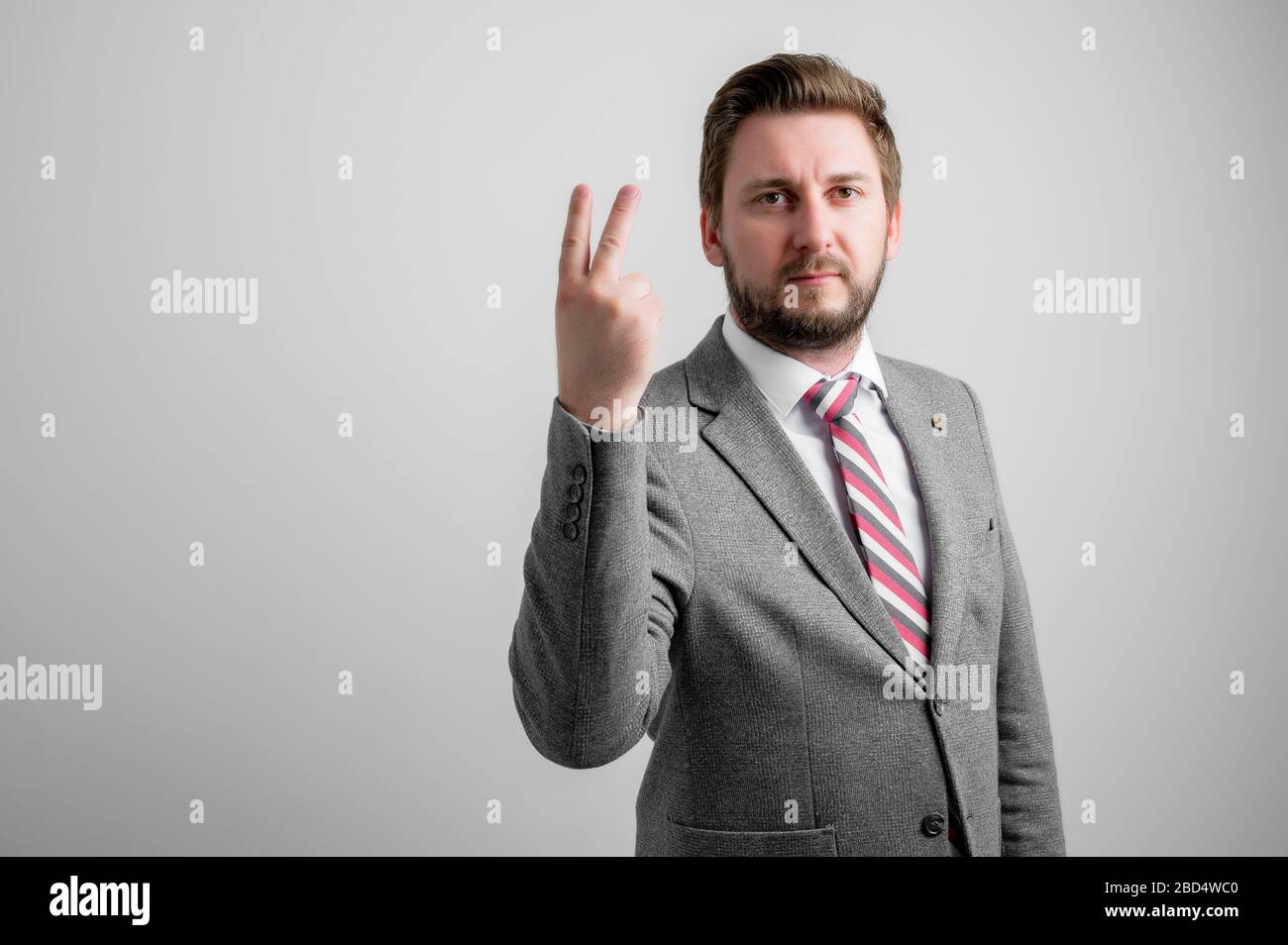 Portrait of business man wearing business clothes showing number two ...