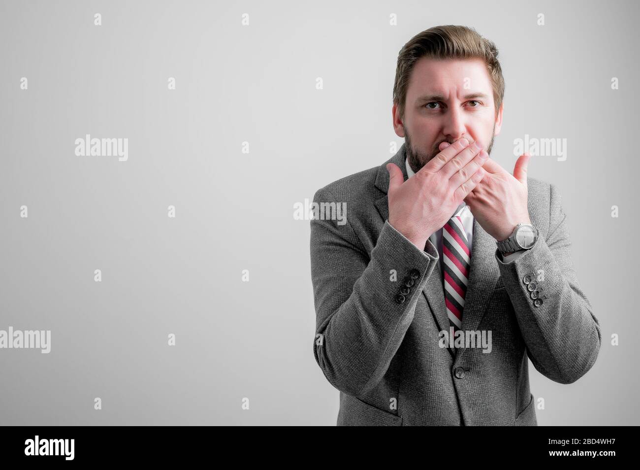 Portrait of business man wearing business clothes covering mouth like ...