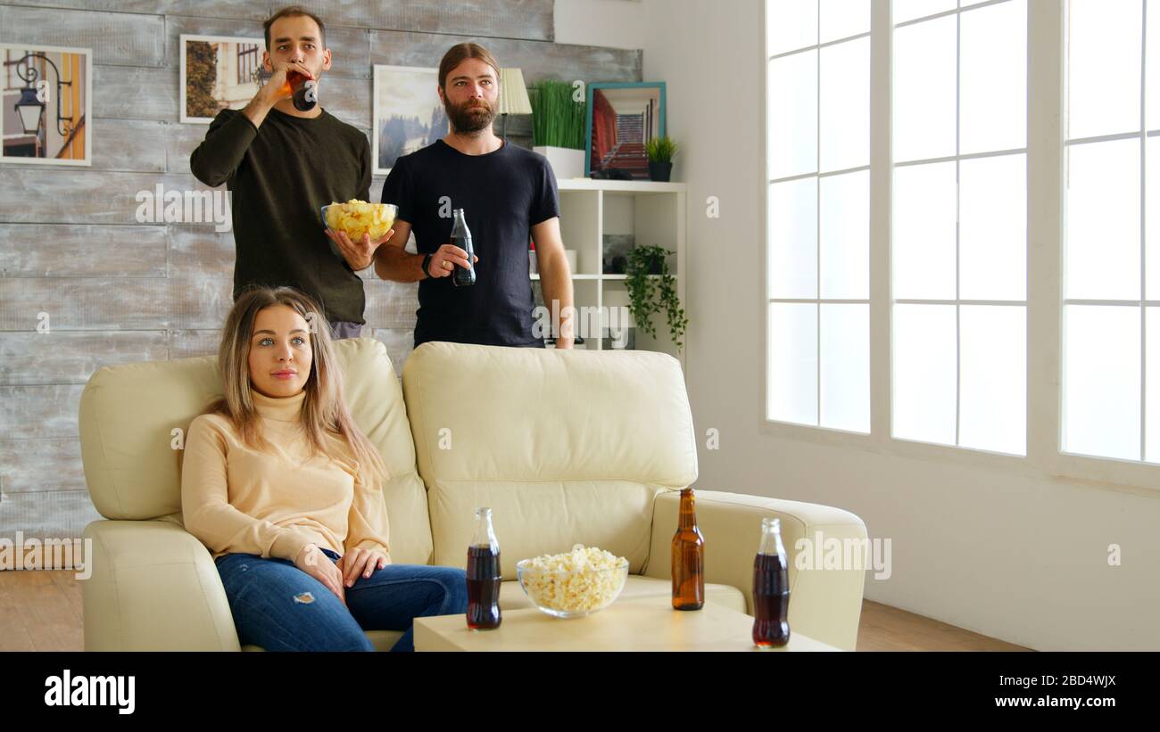 Group of friends sitting on couch reaching out for pizza while watching ...