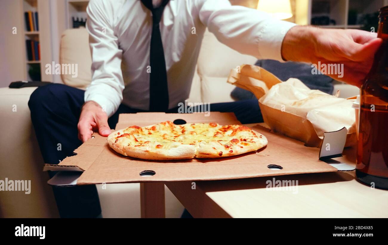 Businessman arriving home with pizza after a long day at work. Resting ...