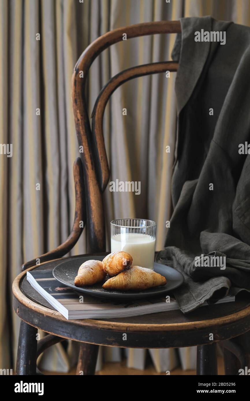 Breakfast with some croissants and milk served on an old chair in the ...