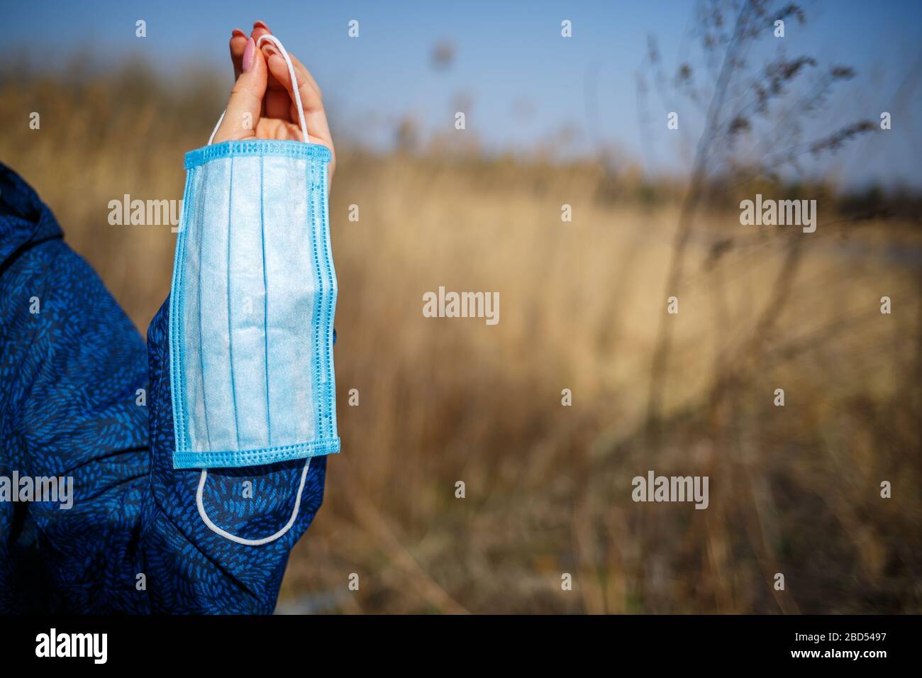 Close up of a surgical mask with rubber ear straps in hand. Typical ...