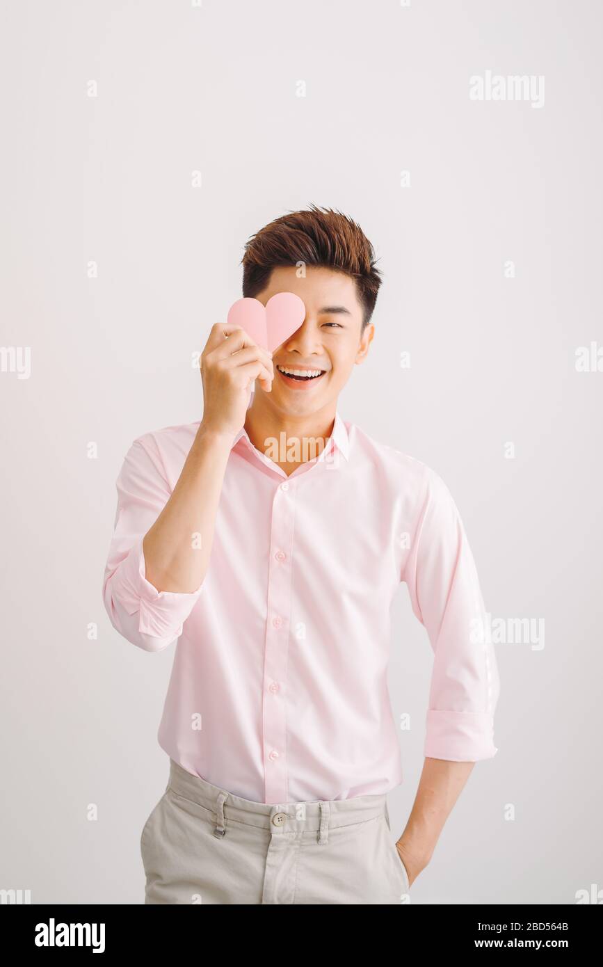 Young handsome asian man reads greeting card with heart shape on white ...
