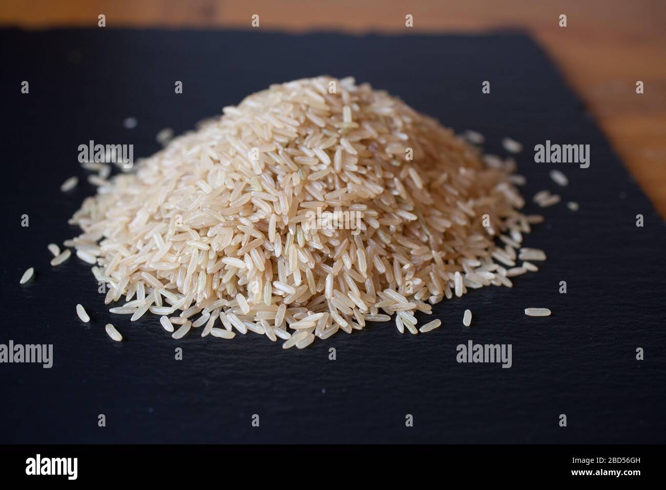 A heap of brown rice photographed on a piece of black slate Stock Photo ...