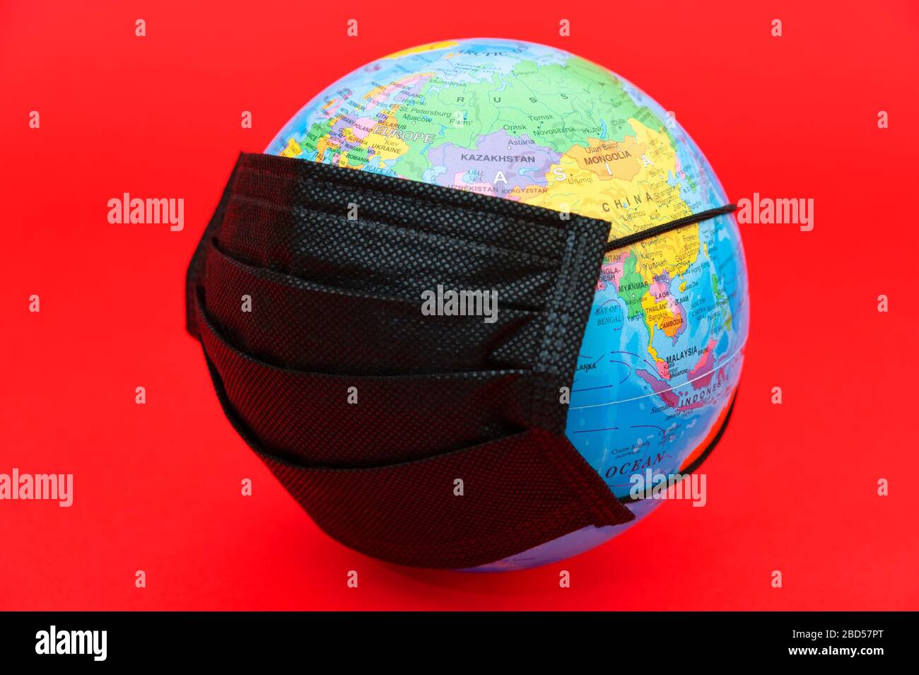 Terrestrial globe model with black surgical mask isolated on red ...