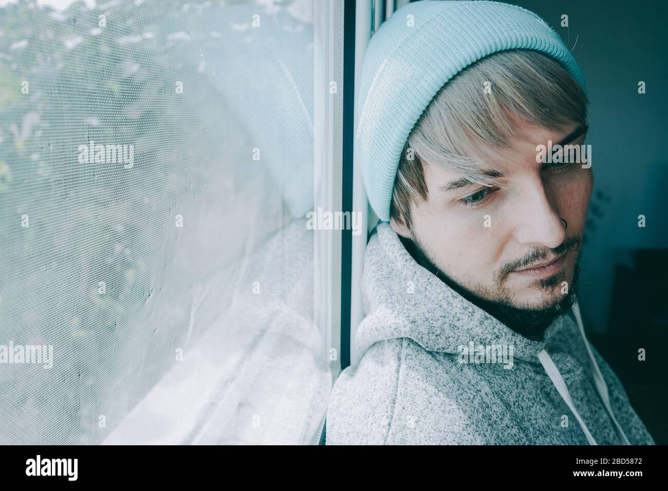Young man alone in his home near a window Stock Photo - Alamy
