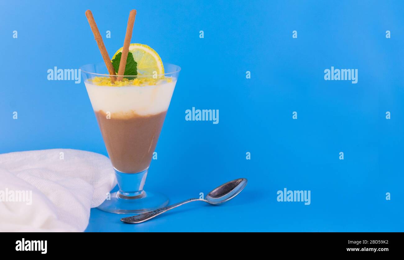 Chocolate vanilla pudding in a glass on a light blue background. Copy ...