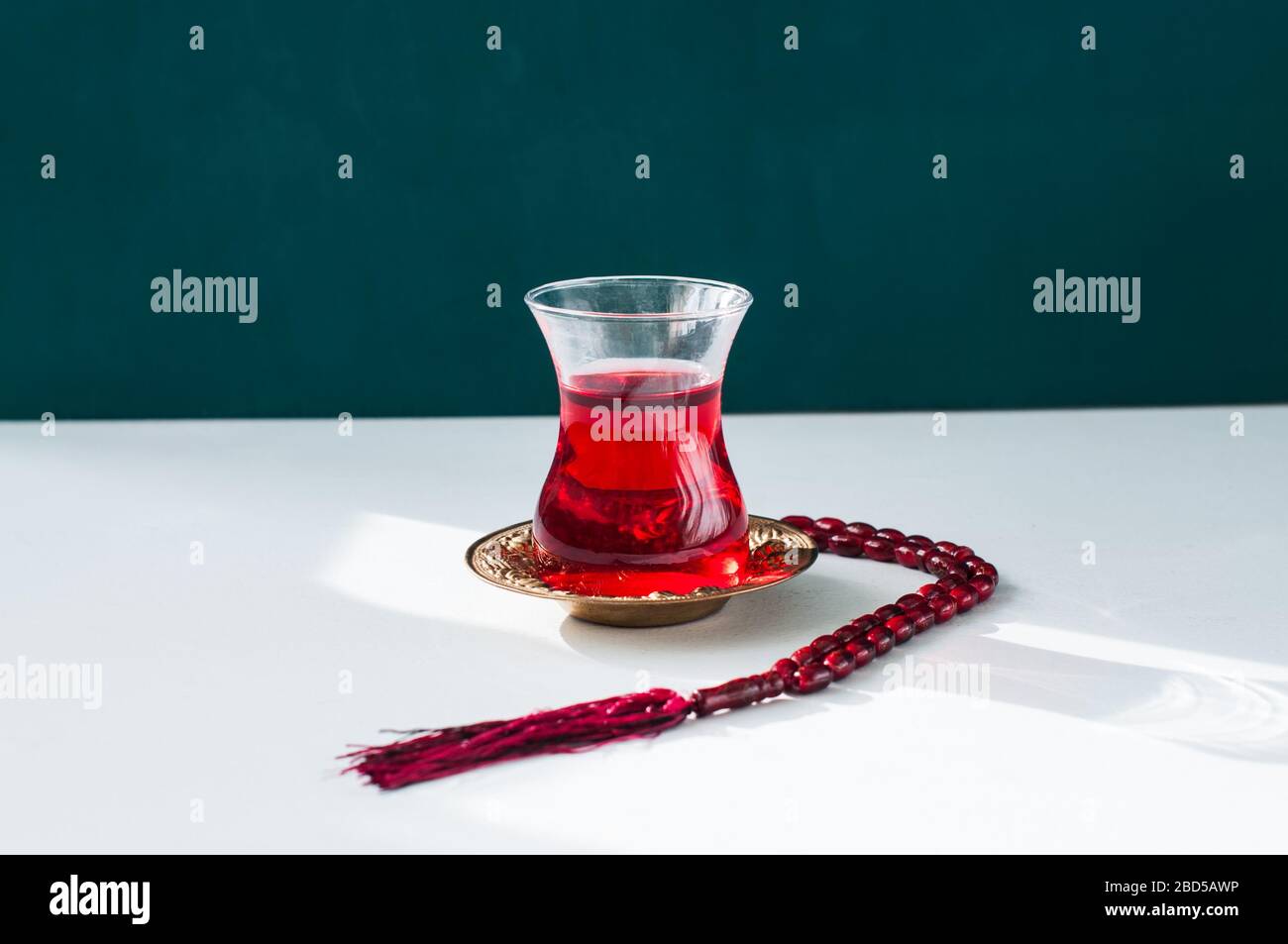 Turkish tea in a glass, muslim beads on a white background. Close up ...