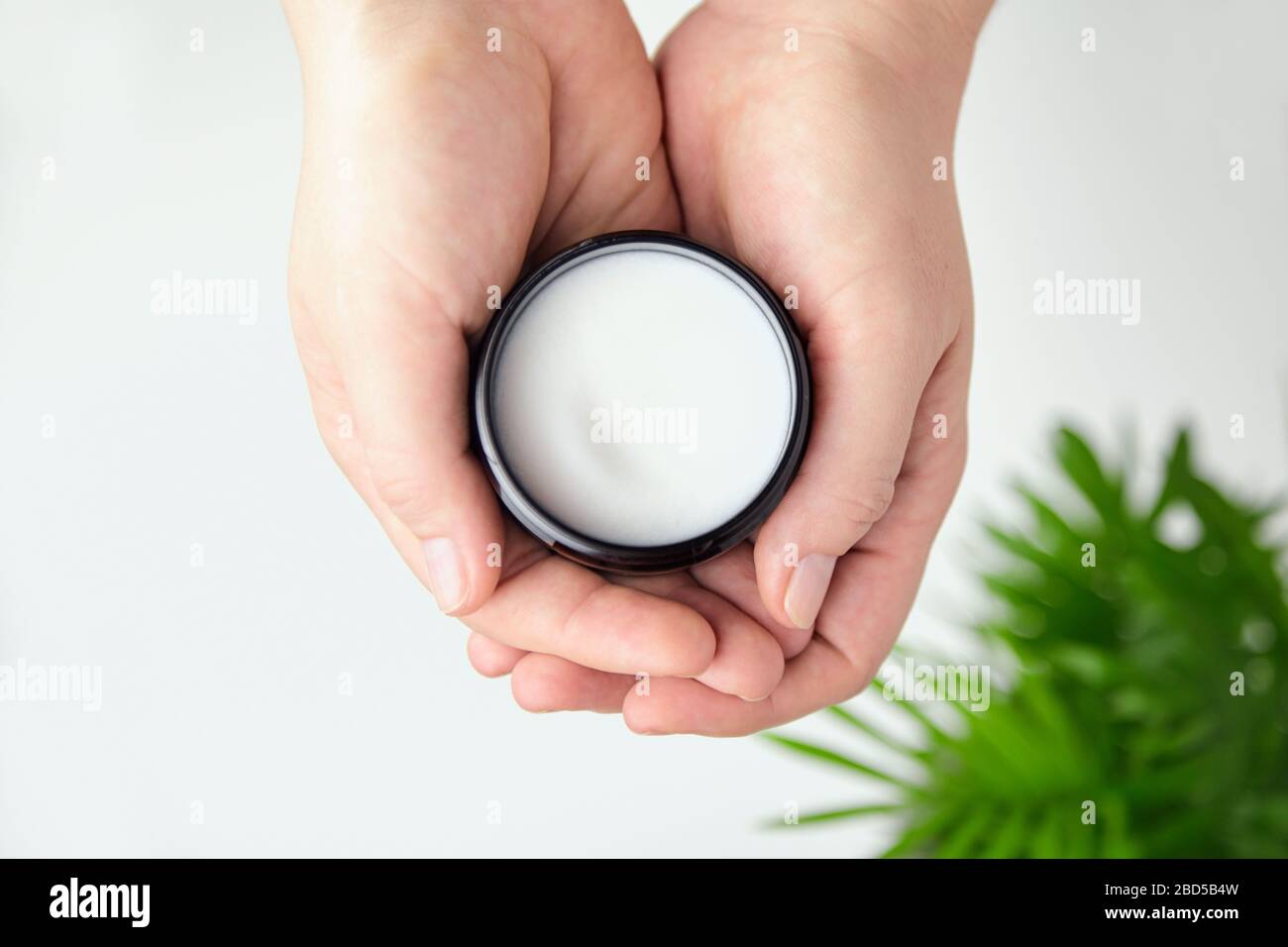 Shea butter in jar, cosmetic product for moisturizing skin. Female hand ...