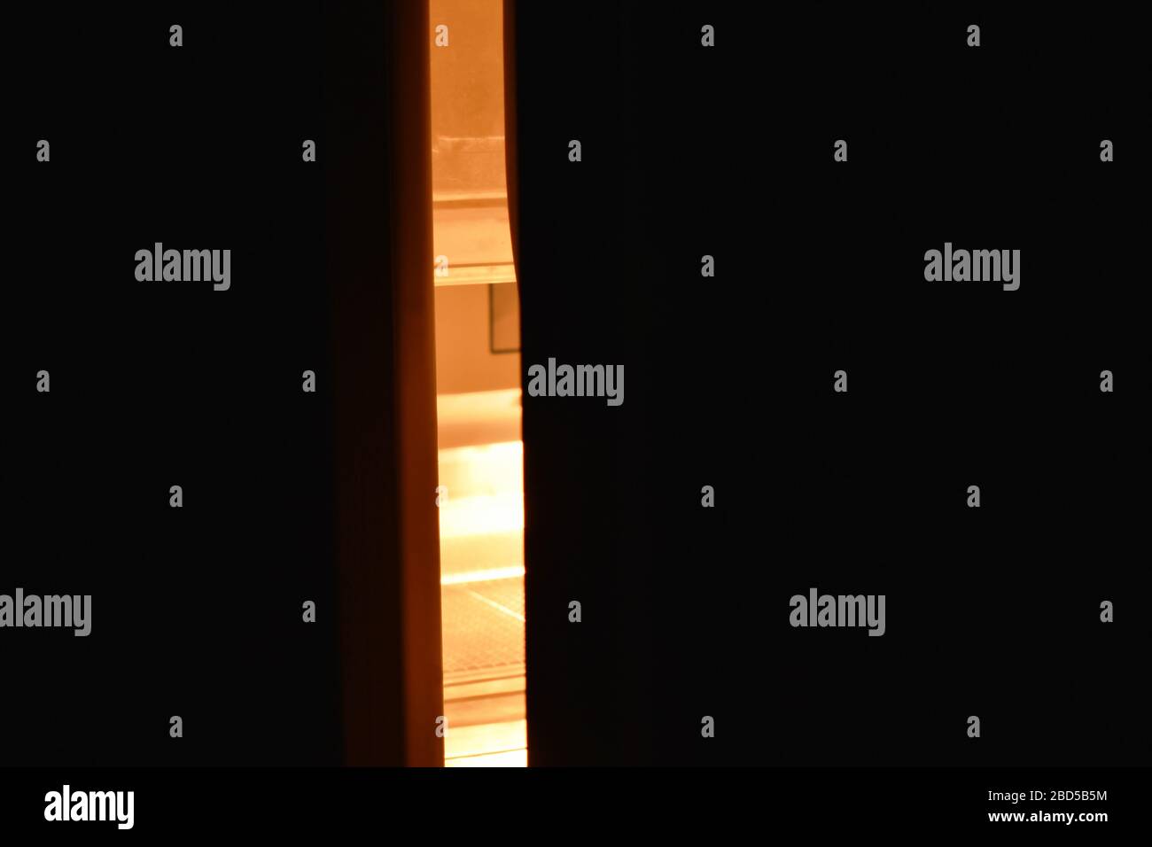 light sift out from refrigerator door ajar out in the dark Stock Photo ...