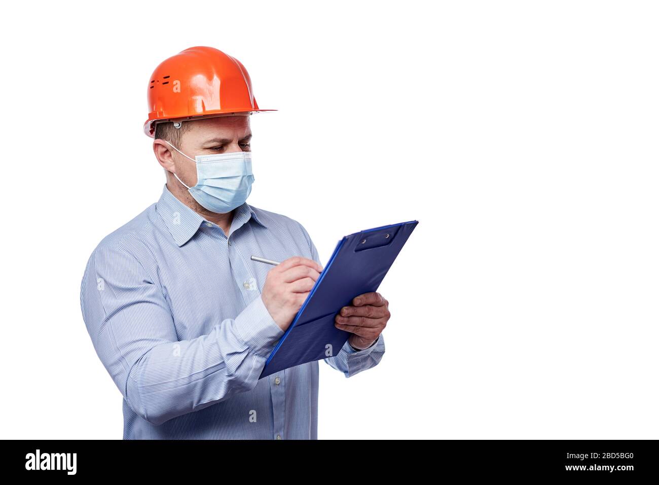 Engineer with face mask and hard hat writing in his clipboard Stock ...